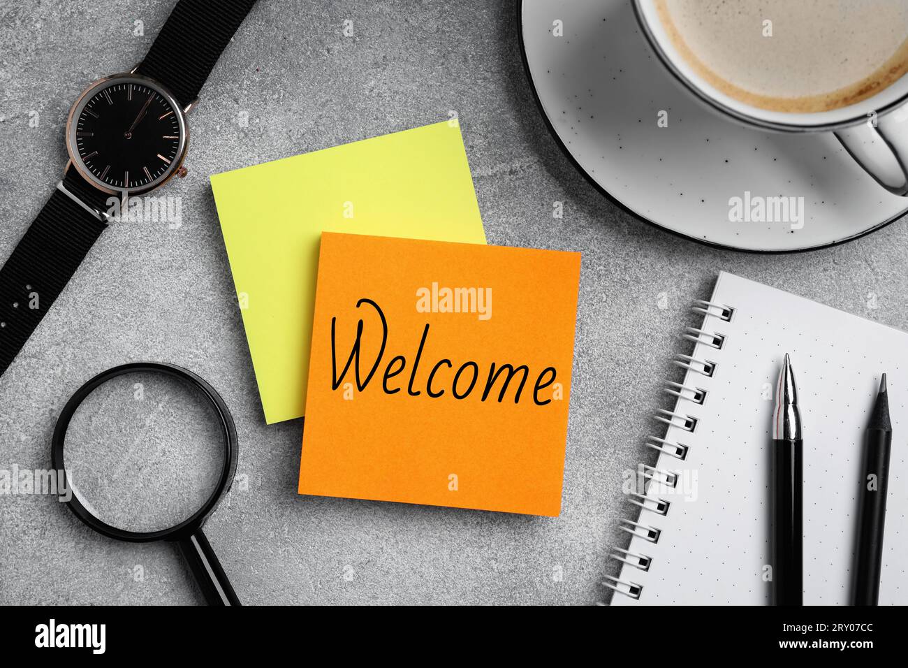 Paper note with word Welcome on grey table. Office desk with stationery ...