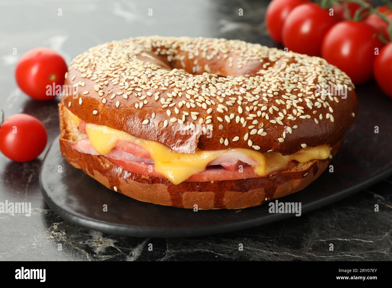 Delicious bagel with ham and cheese on dark marble table, closeup Stock ...