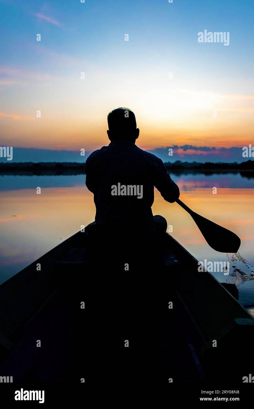 Silhouette of a native man paddling canoe at dusk calm water Stock ...