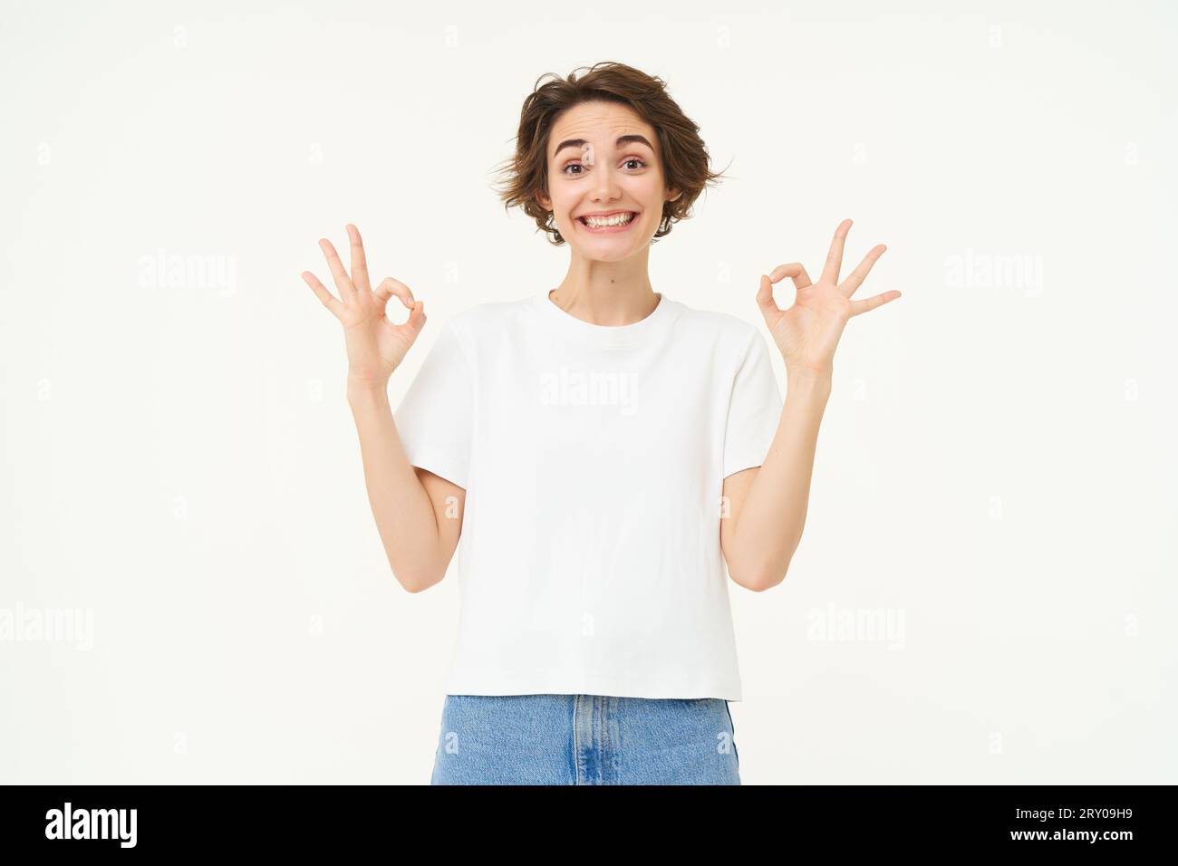 Portrait of young woman, showing okay, ok gestures and smiling, giving ...