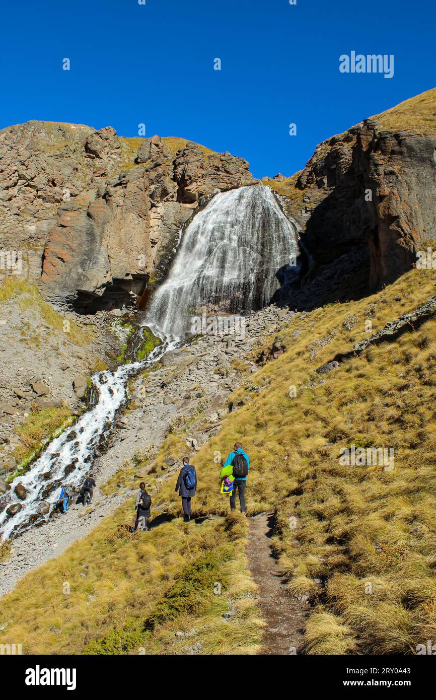 Hikers are walking on the trail towards big mountain waterfall known as ...