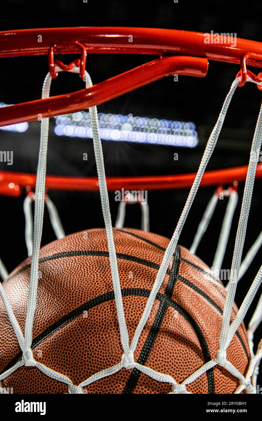 A close-up view looking up at the top of an orange basketball falling ...