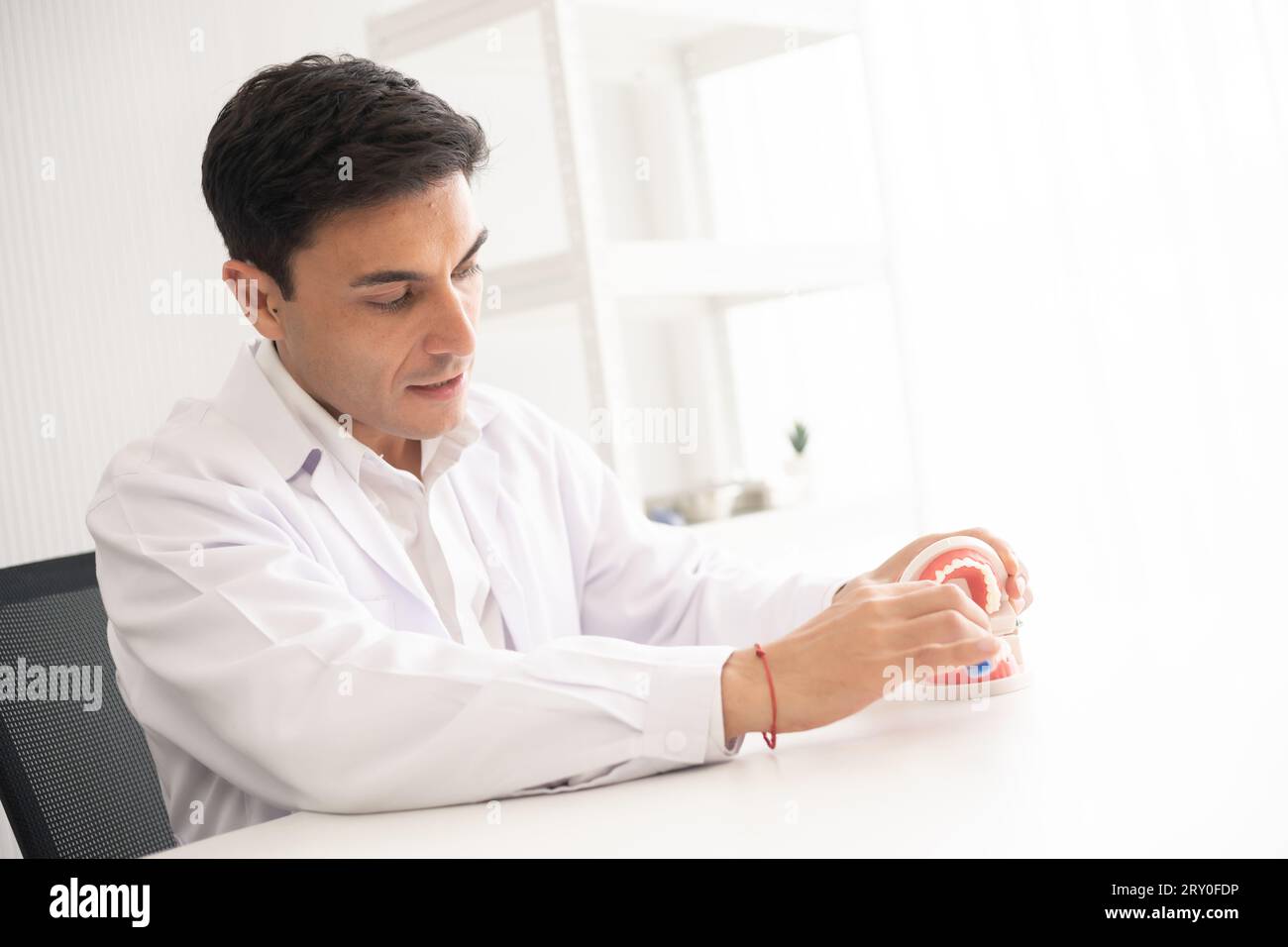 Hispanic dentist explaining to patient about teeth and how to brush ...