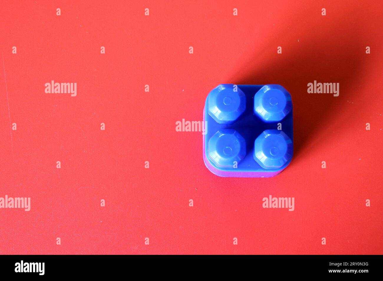 Buildable blue plastic block on a red background. Concept of loneliness ...