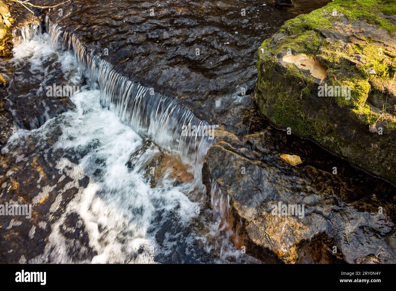 The water in the stream flows down the limestone rapids. small ...