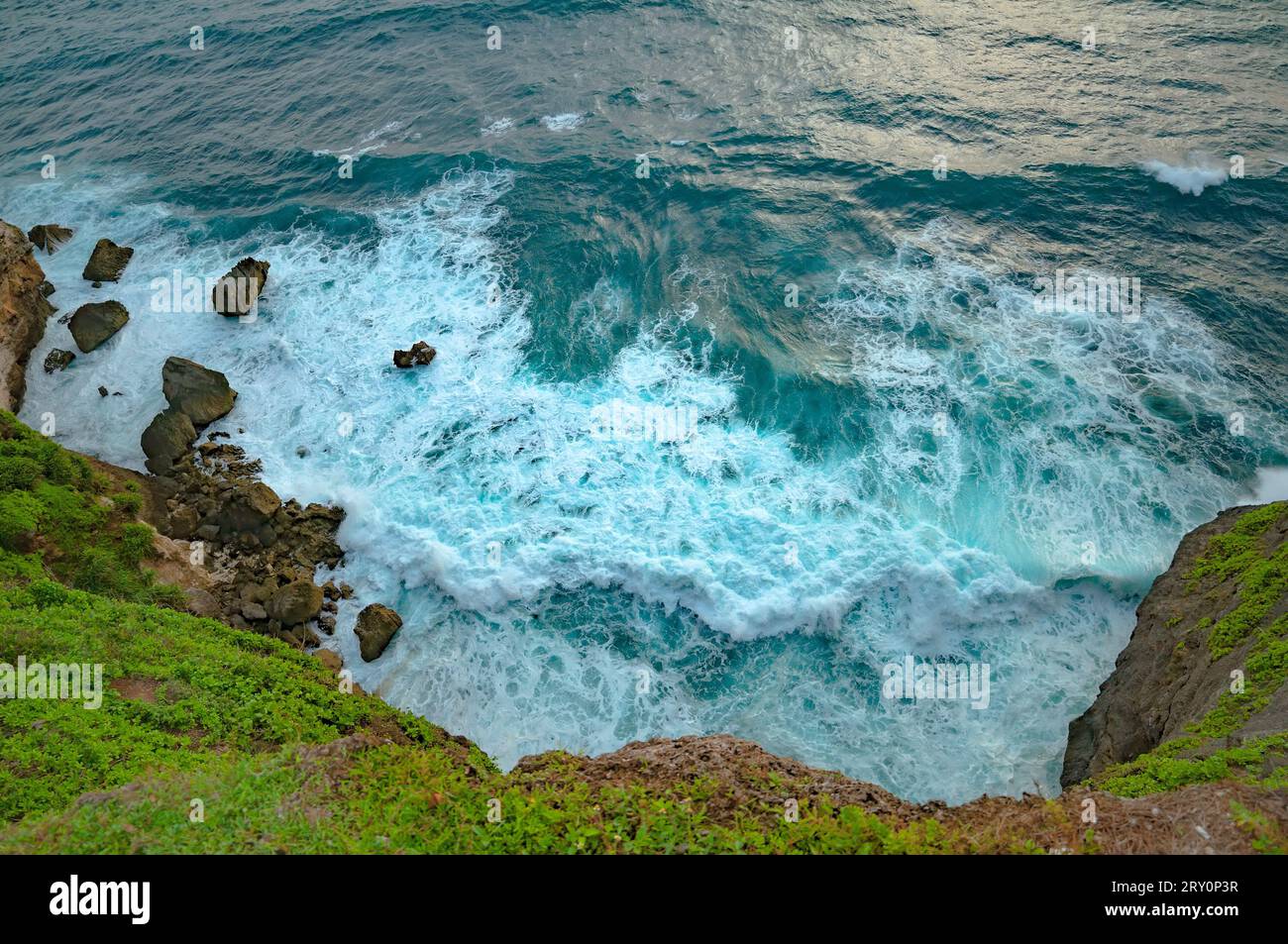Ocean waves beat against the steep bank of the island of Bali ...