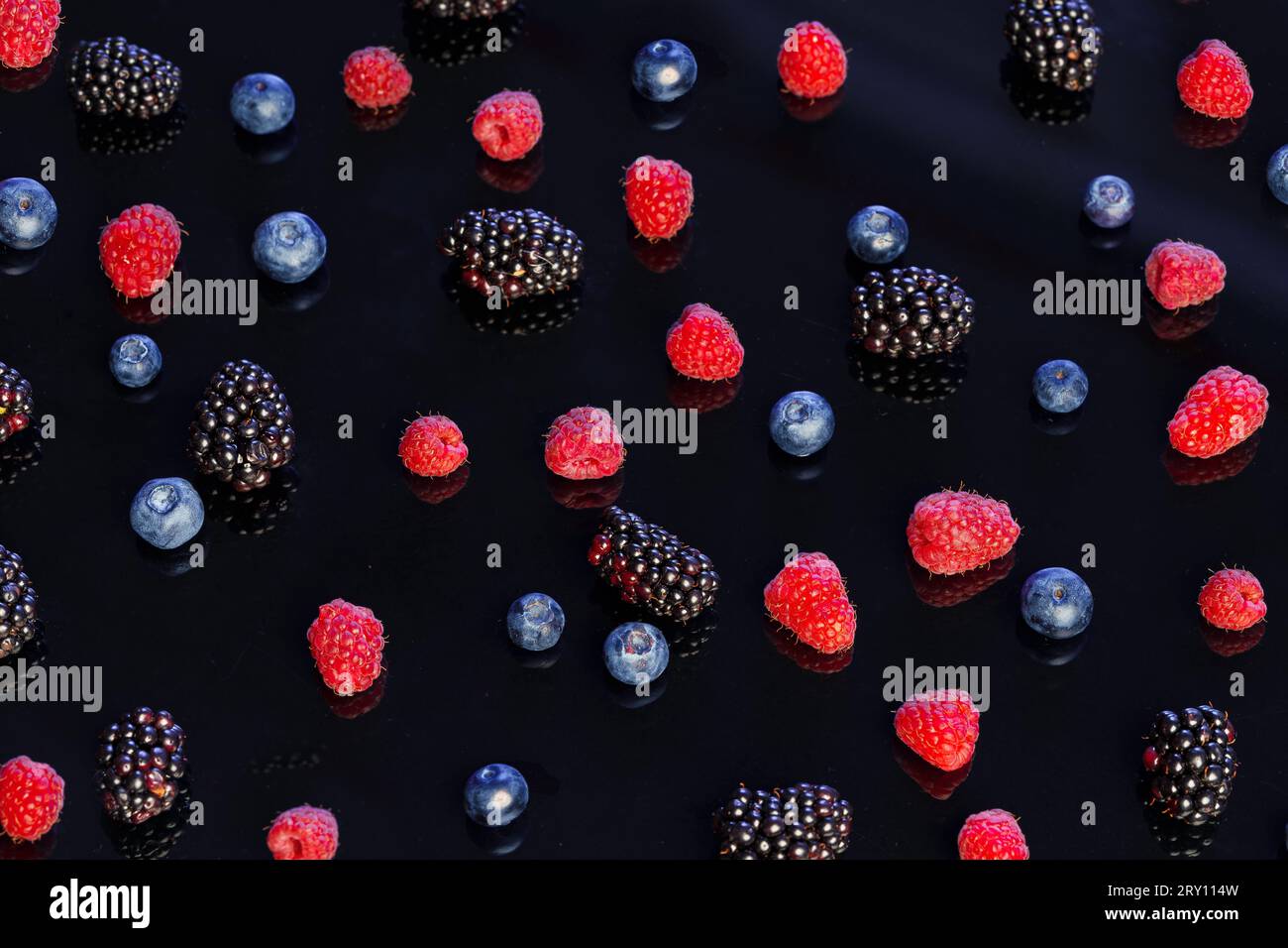 Fresh wild berries scattered on black background Stock Photo - Alamy