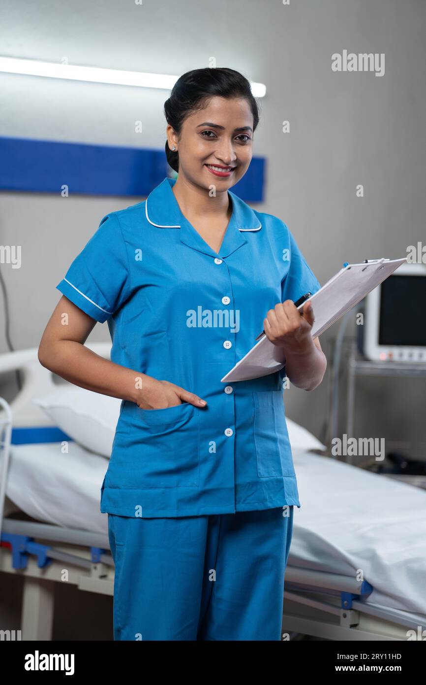 vertical shot Happy Smiling Nurse with Clipboard standing confidently ...