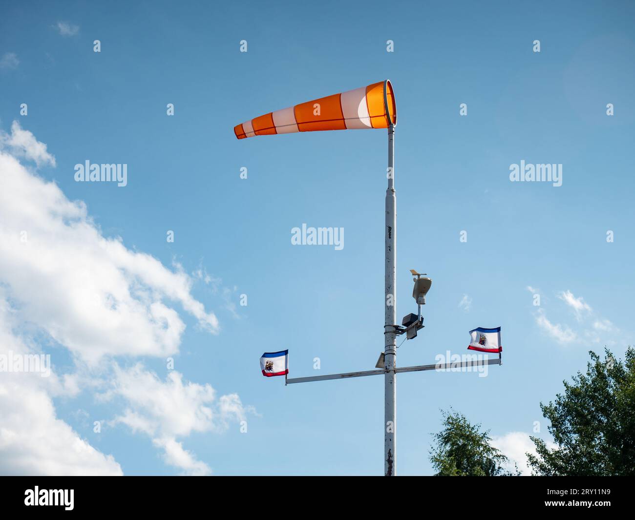 Windscock and flag flutter in the wind on a tall pole. The weather ...