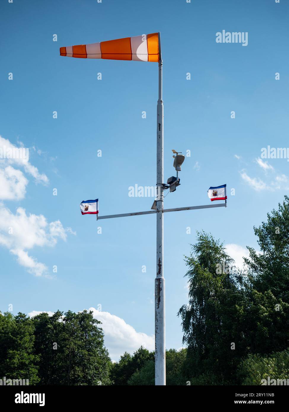Windscock and flag flutter in the wind on a tall pole. The weather ...