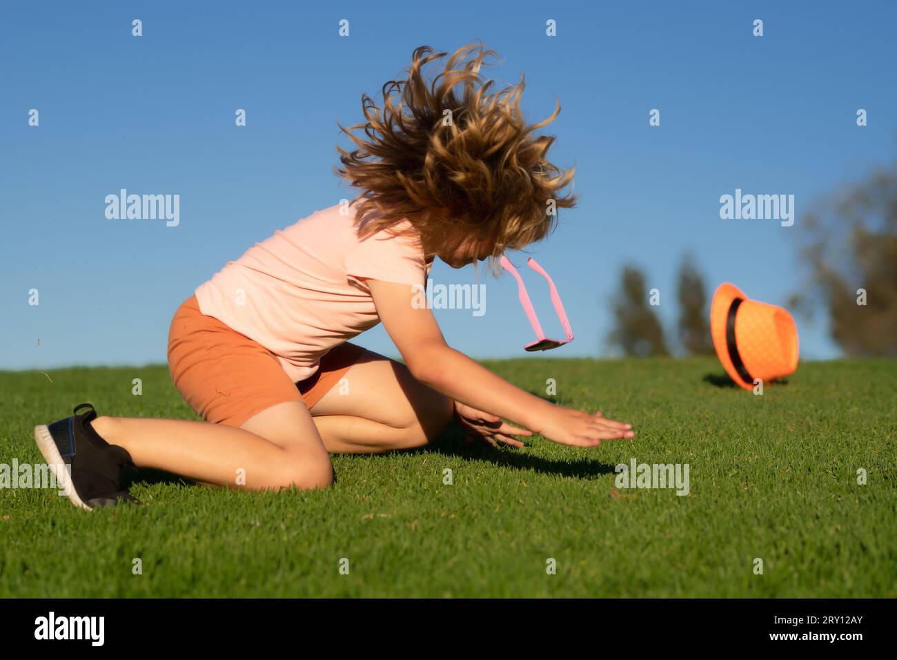 Kid boy fall down on the ground in summer park. Moment of the fall down ...