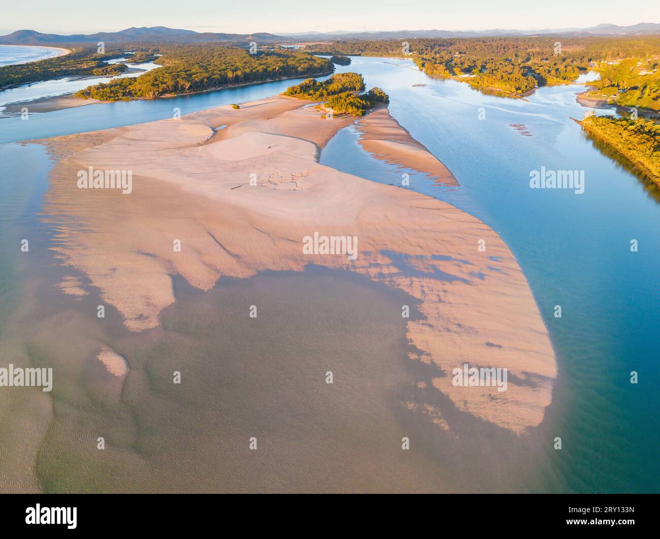 Aerial view of a coastal river flowing out to sea past islands and sand ...