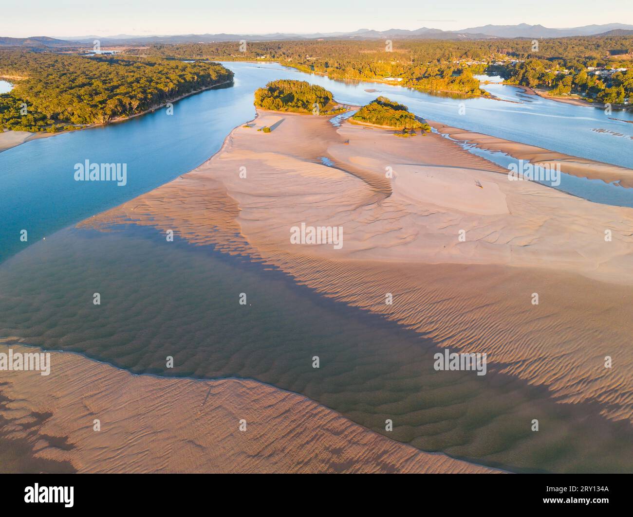 Aerial view of a coastal river flowing out to sea past islands and sand ...