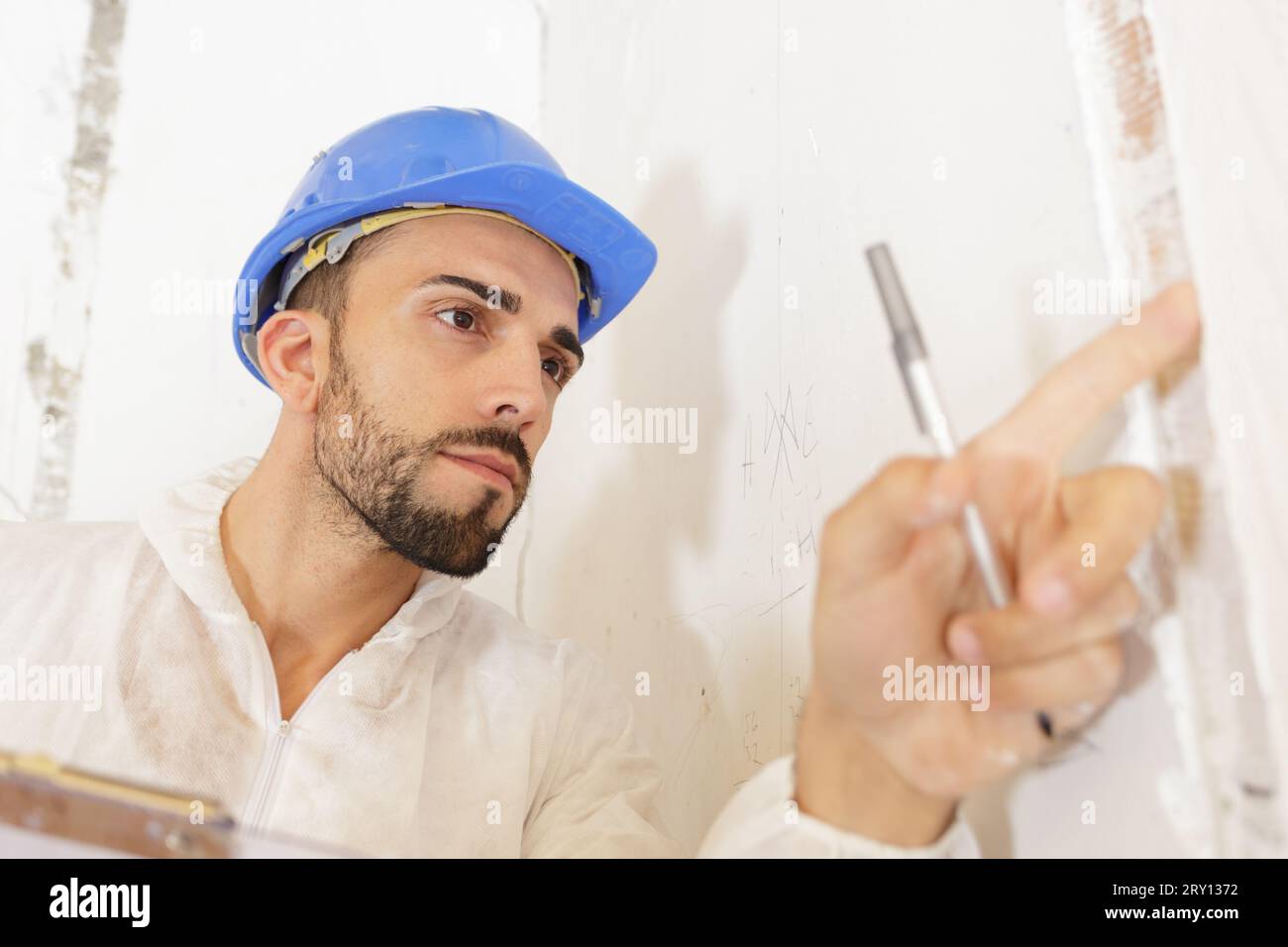 a male builder inspecting wall Stock Photo - Alamy