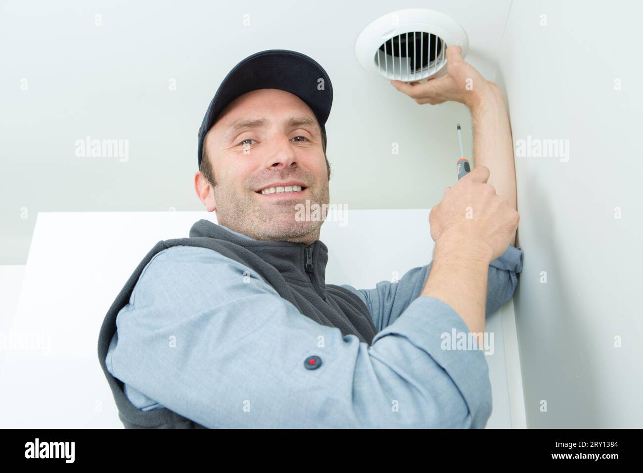 portrait of man fitting ceiling vent Stock Photo - Alamy
