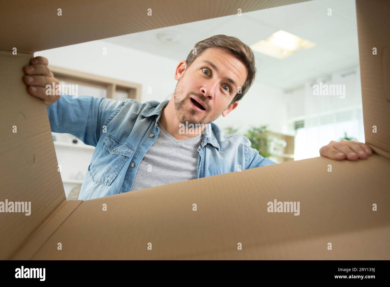 surprised man unpacking a box Stock Photo - Alamy
