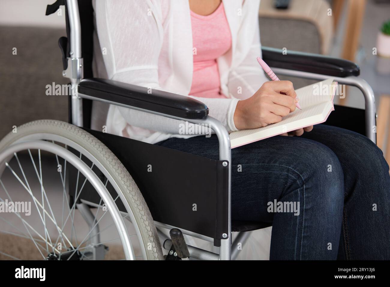 cropped image of woman in wheelchair writing in book Stock Photo - Alamy