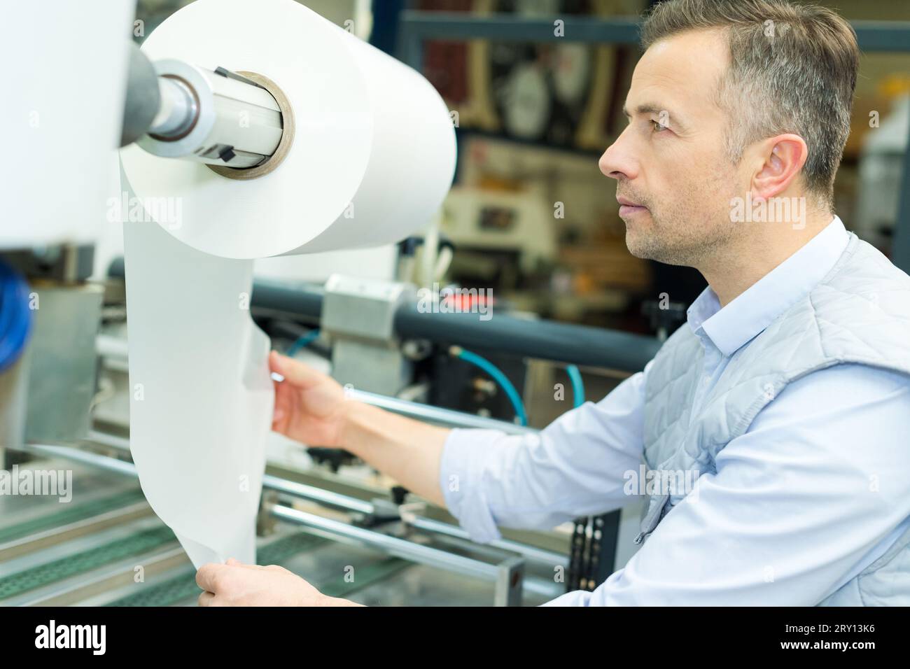 industrial printing press worker looking at rolled paper Stock Photo ...