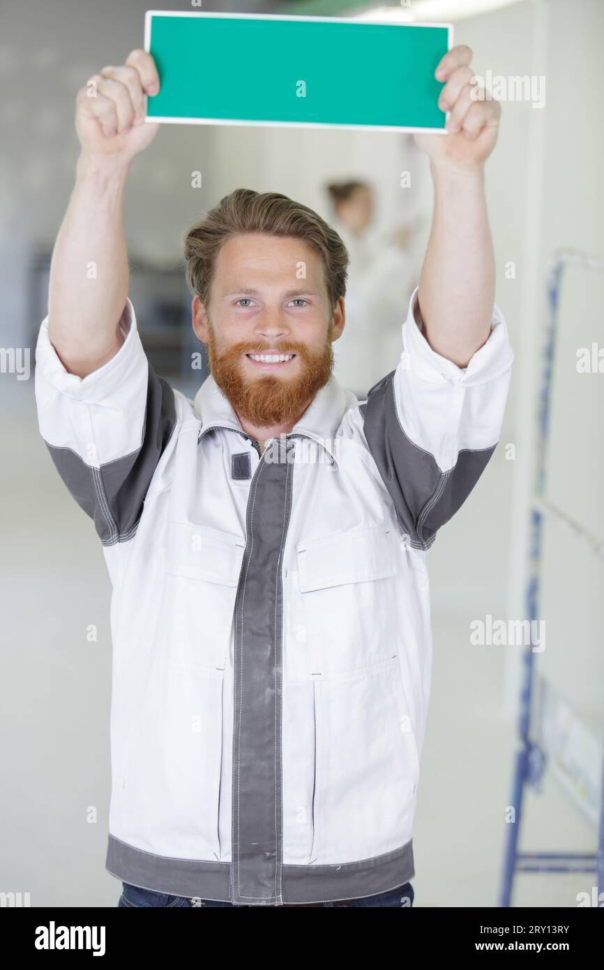 tradesman holding a wet paint sign Stock Photo - Alamy