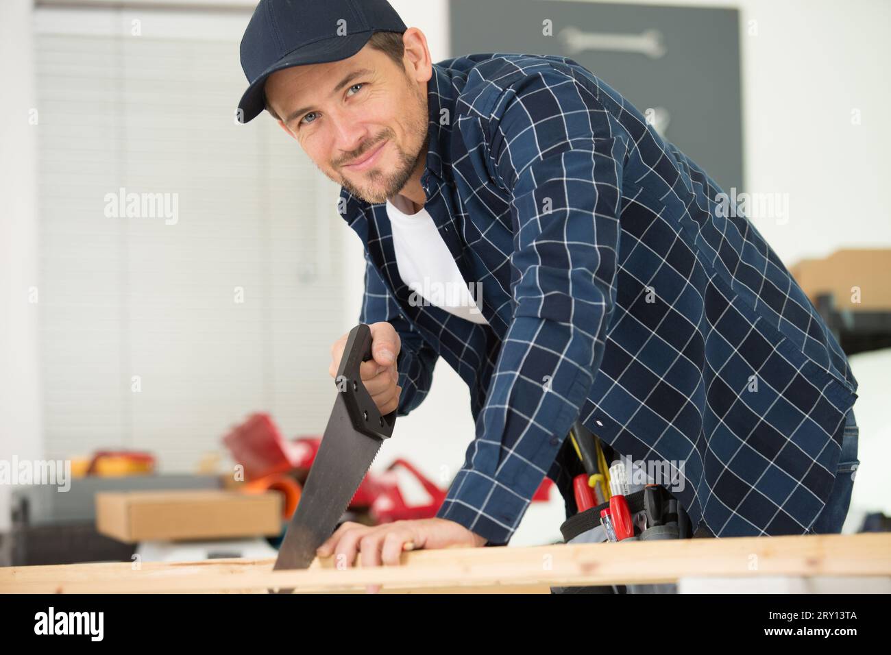 portrait of handsome cheerful master using a handsaw Stock Photo - Alamy