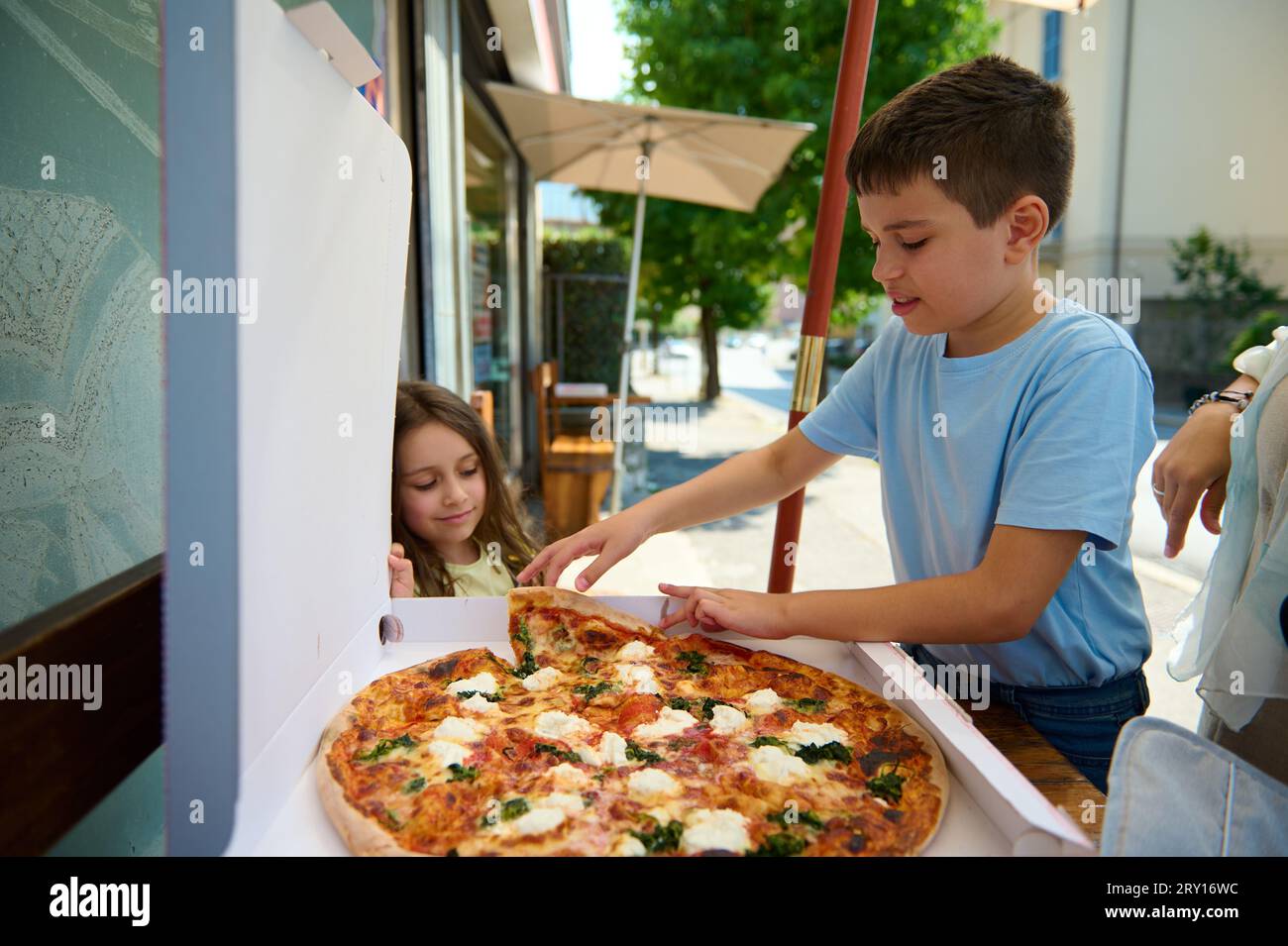 Adorable children, a teenage boy and little kid girl snacking outdoors ...
