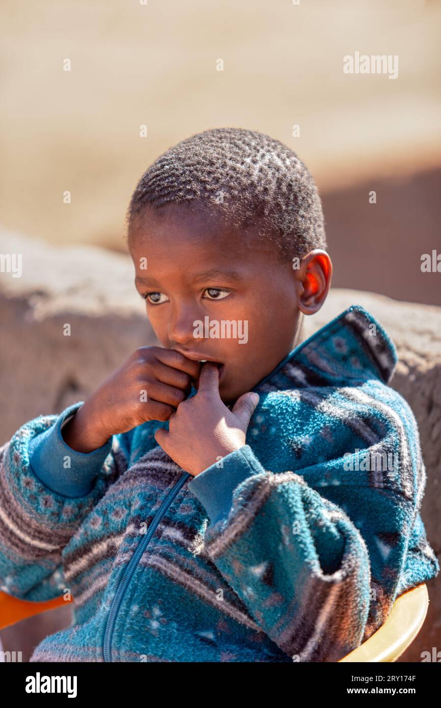 african child standing in front of his house in the village on a ...