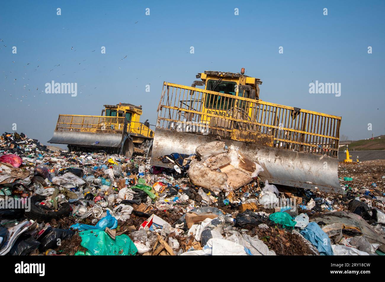 Municipal waste landfill. Workers with trucks and bulldozers at work in ...