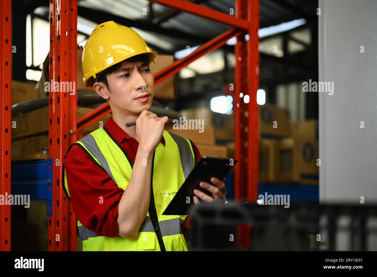 Warehouse manager checking stock and order details while standing near ...