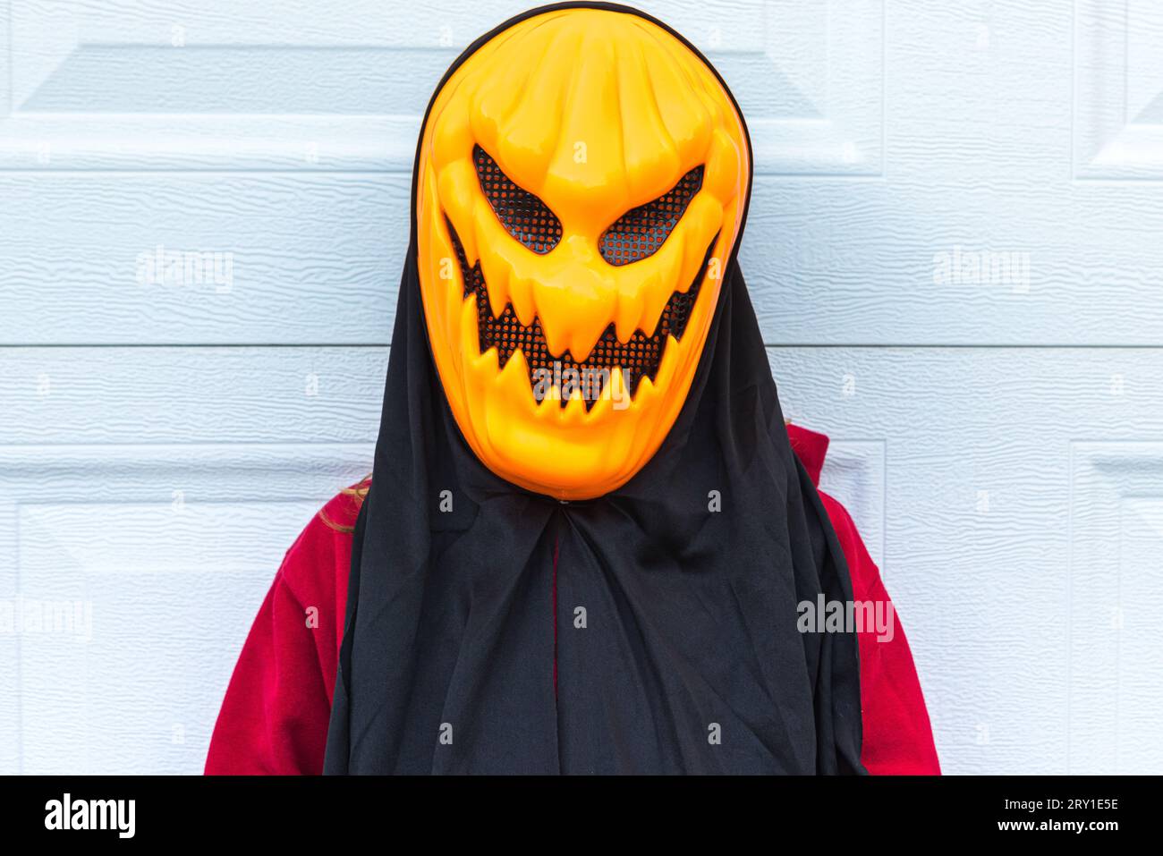 Close-up of a child girl wearing a scary Halloween pumpkin mask ...