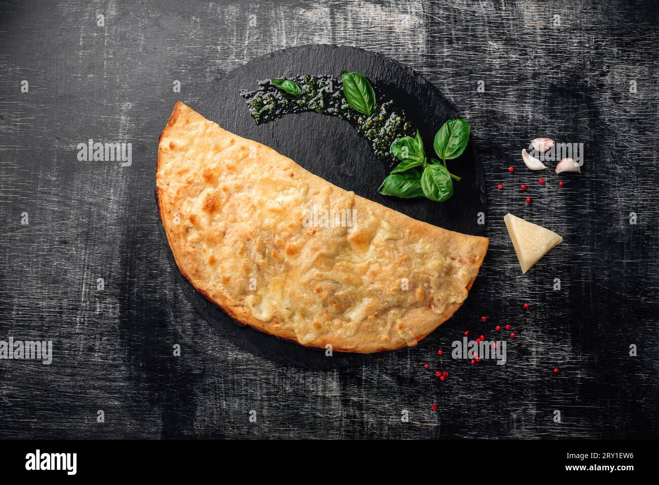 Traditional Italian pizza calzone with ingredients on a stone and dark ...
