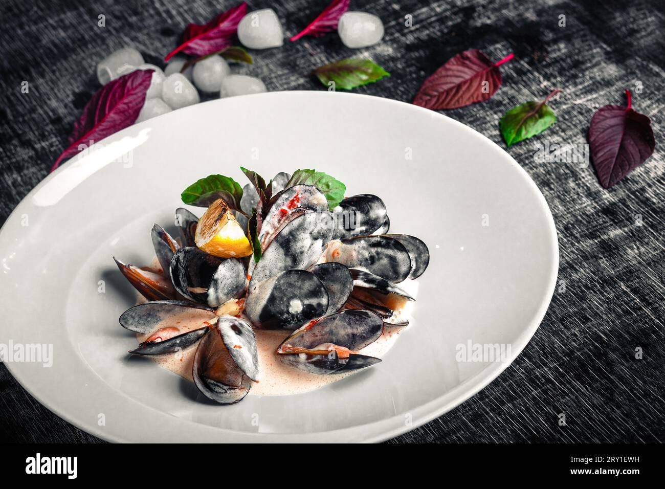 Seafood mussels in cream sauce with lemon and basil on a black chalk ...