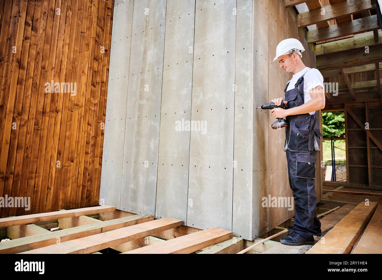 Carpenter constructing wooden framed house. Man worker cladding facade ...