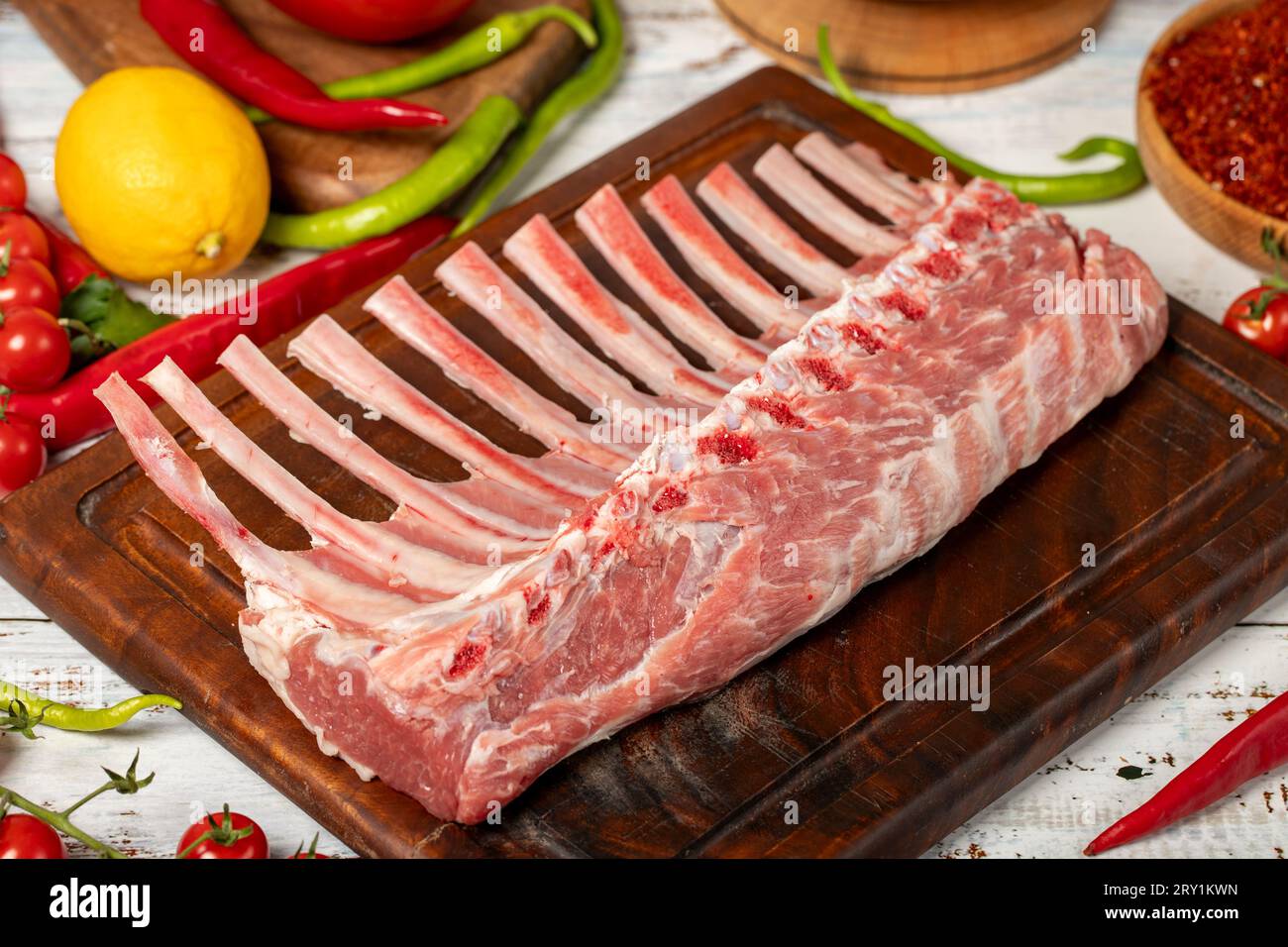 Lamb rack cutlet on wood background. Raw lamb chops with herbs and ...