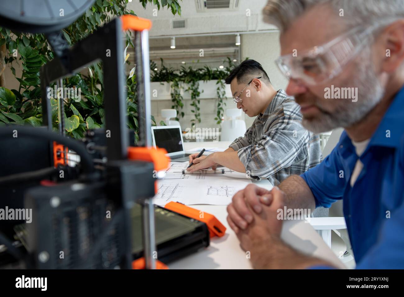 Architects working with 3D printer and projecting house model, drawing ...