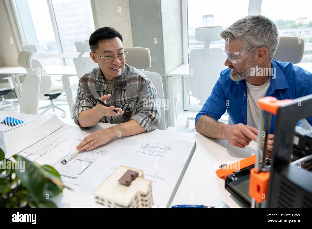 Architects working with 3D printer and projecting house model, drawing ...