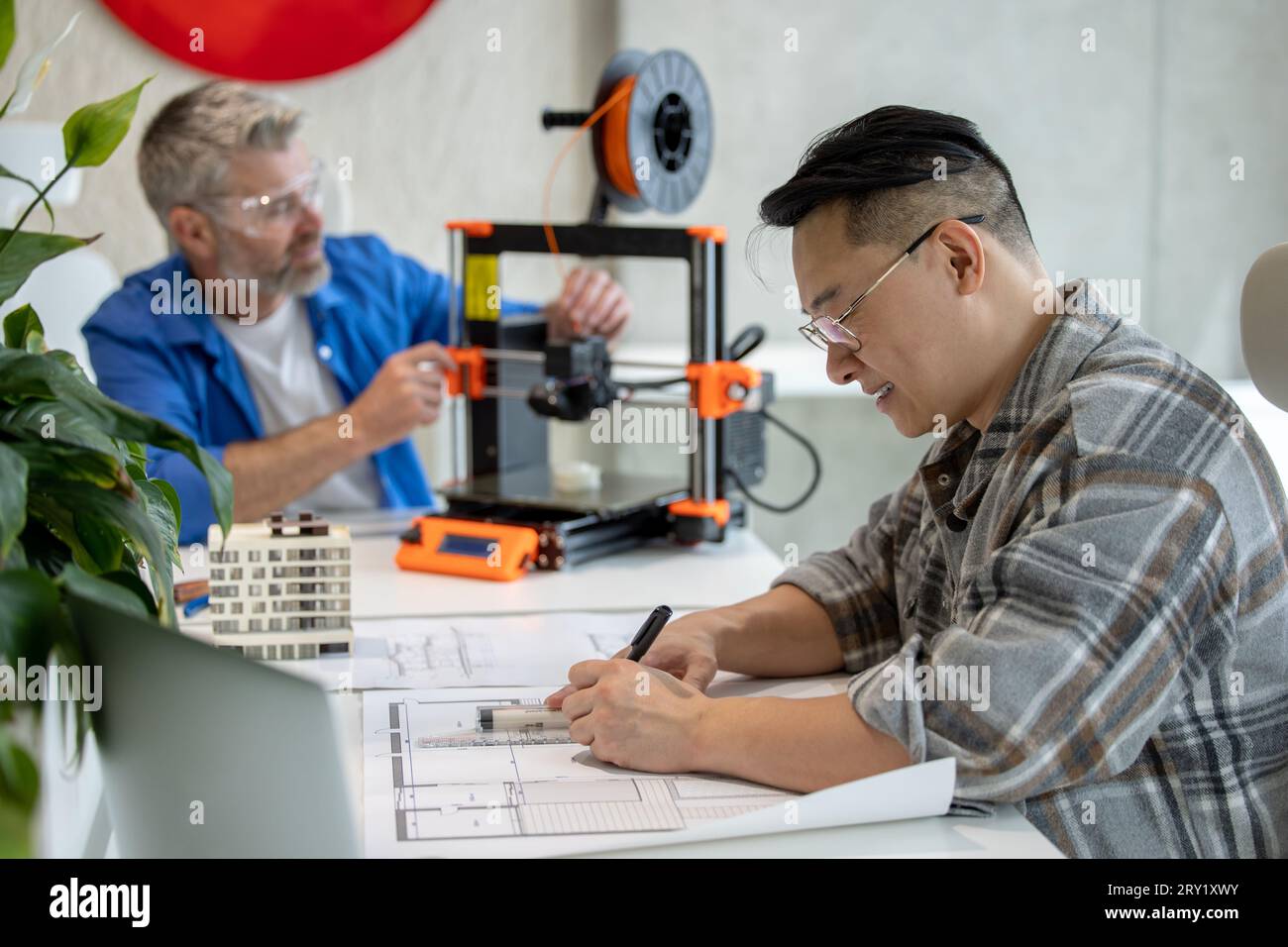 Architects working with 3D printer and projecting house model, drawing ...