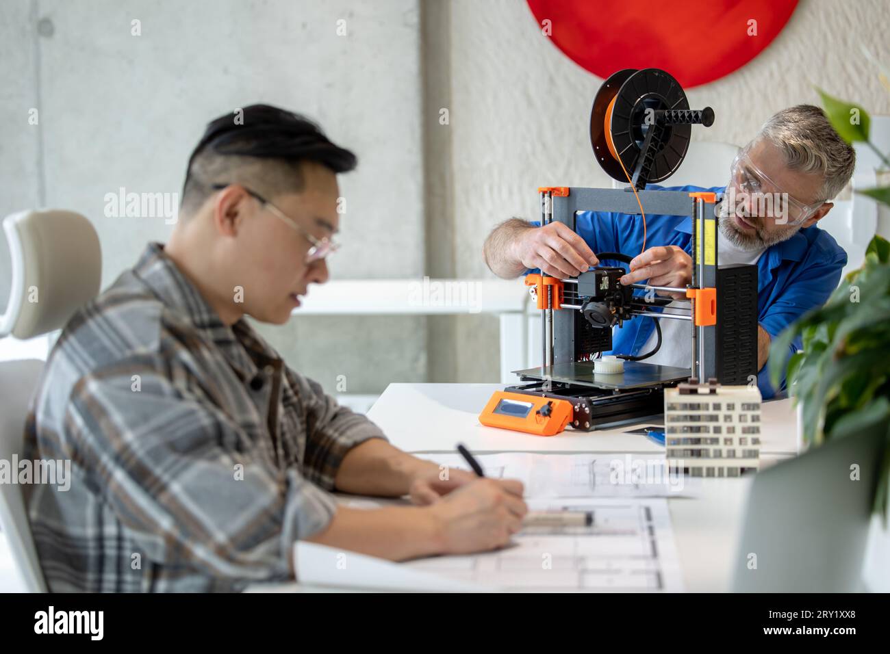 Architects working with 3D printer and projecting house model, drawing ...