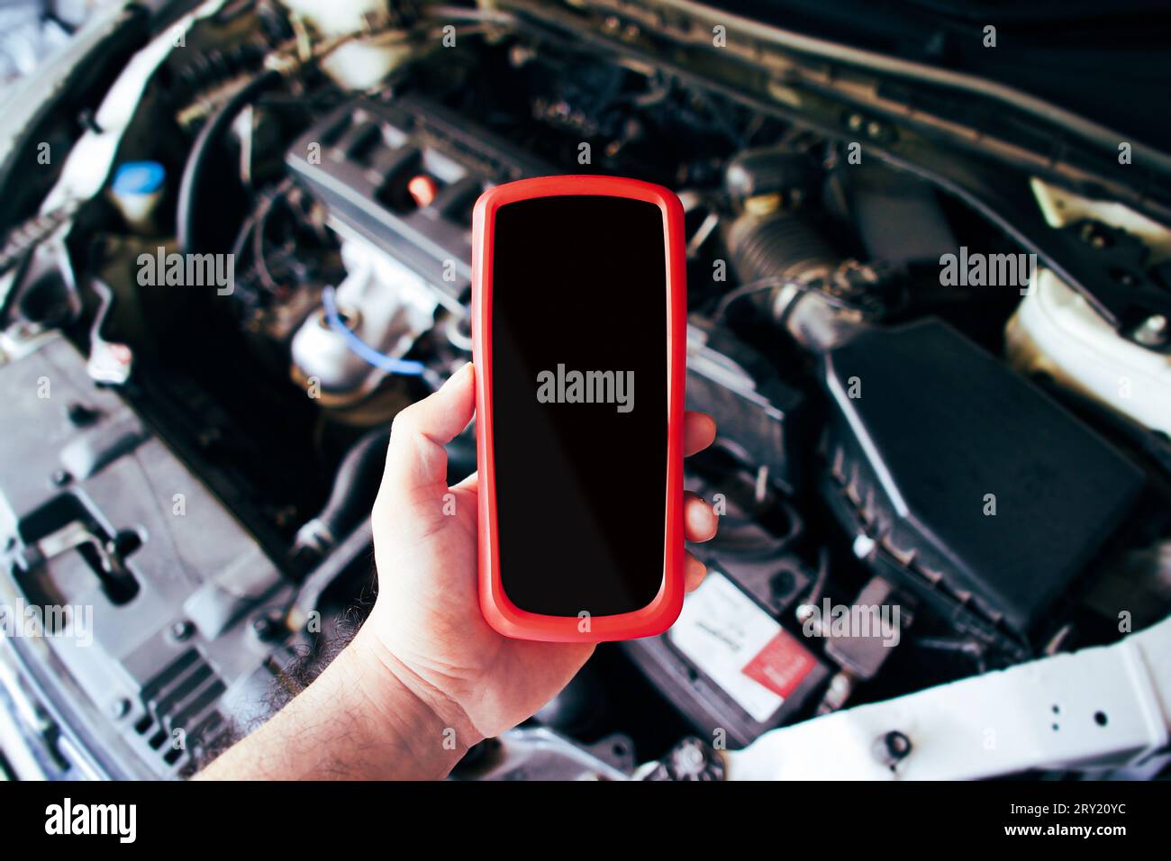 Blank black screen of OBD2 scanner tool in a mechanic hand with a car ...