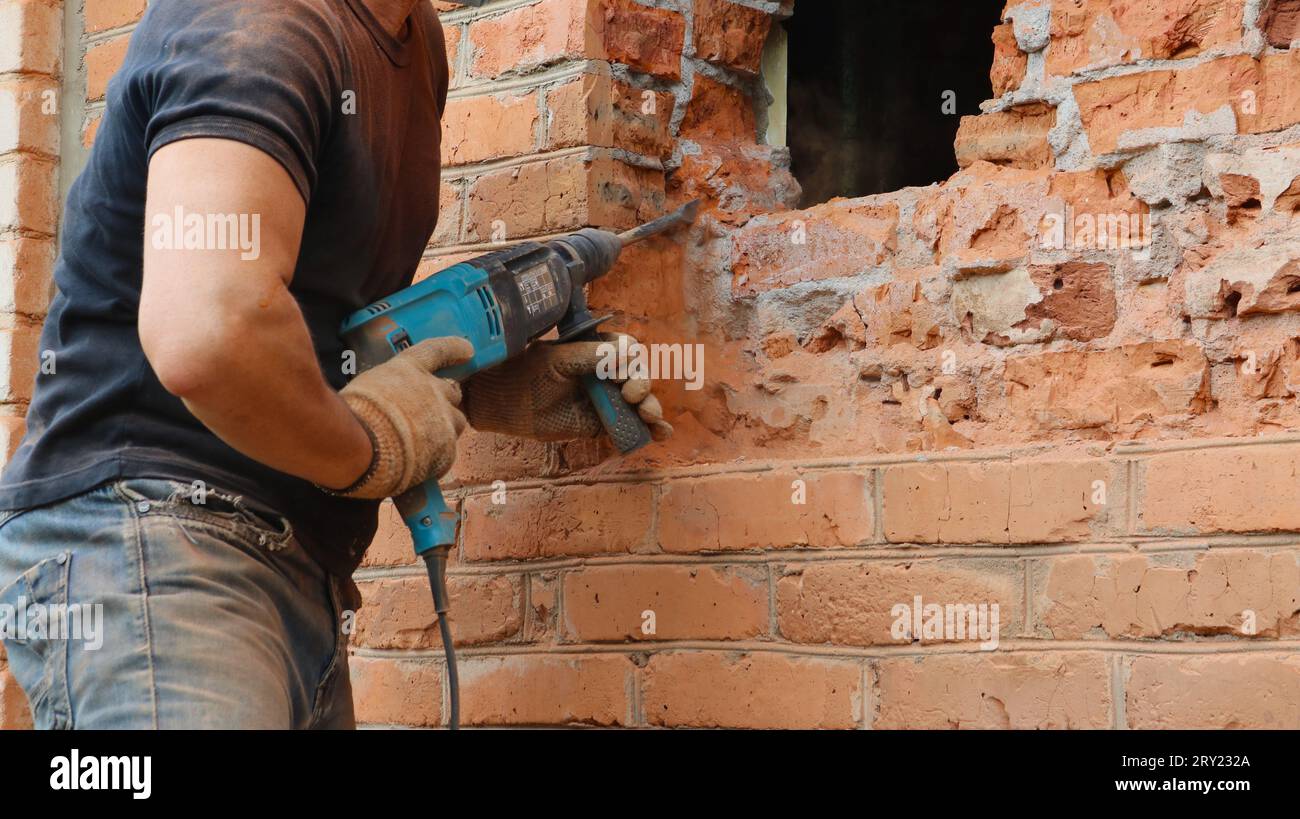 construction worker chiseling brickwork wall with a jackhammer ...