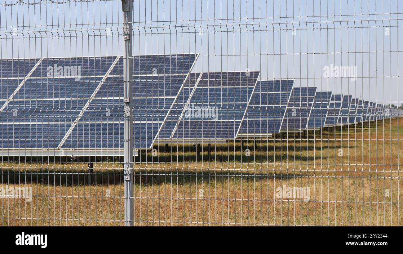 solar power plant with many panels fenced with barbed wire fence ...