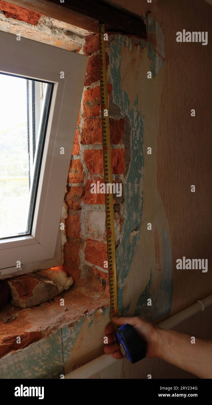 a vertical image where a builder, invisible in the frame, uses a tape ...