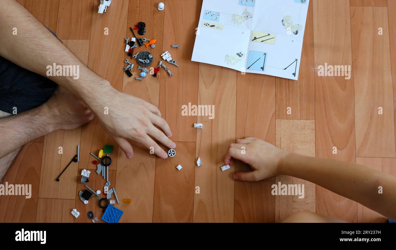 a man and a boy assemble a construction set from small parts together ...