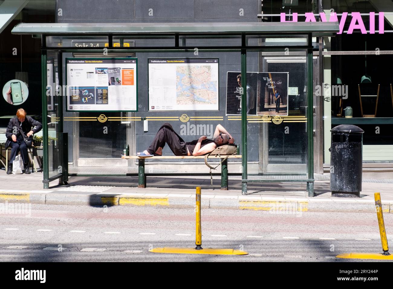 A man sleeping waiting in a bus shelter outside the Central Bus Station ...