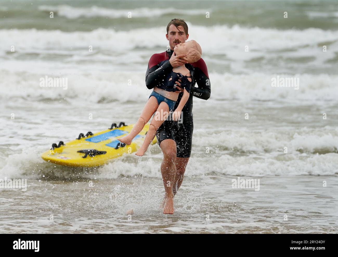 An RNLI Lifeguard carries a dummy of a child from the sea during a ...