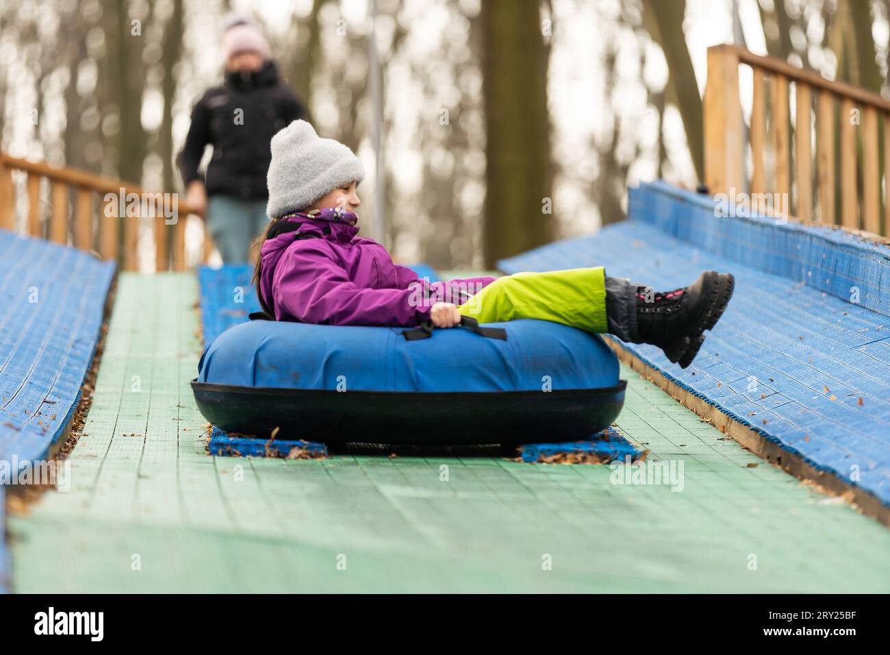 Little girl sliding downhill on tube Stock Photo - Alamy