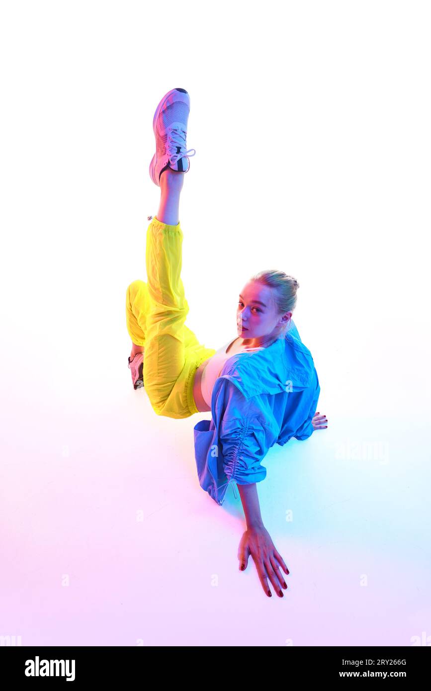 View from top of young girl training, raising one leg in trendy sport ...