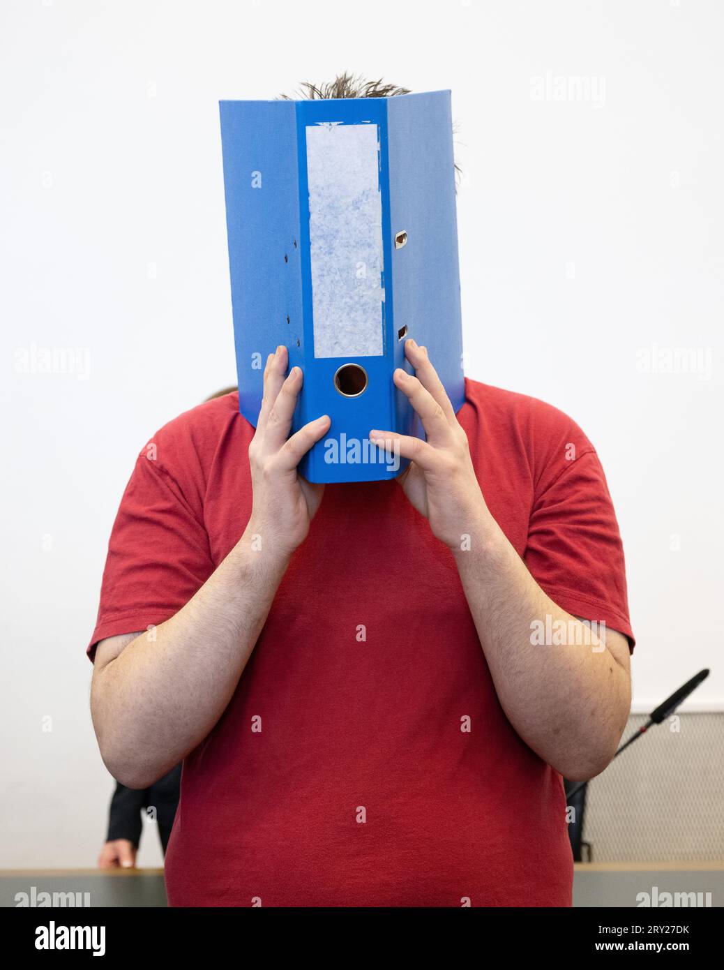 28 September 2023, Hesse, Gießen: The defendant holds a file folder in ...