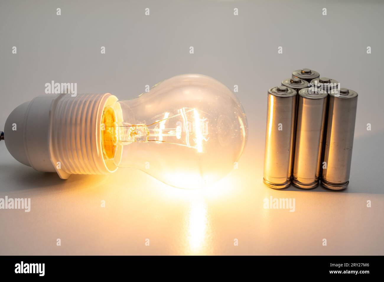 Light bulb turned on, with batteries next to it. Accumulation and reuse ...