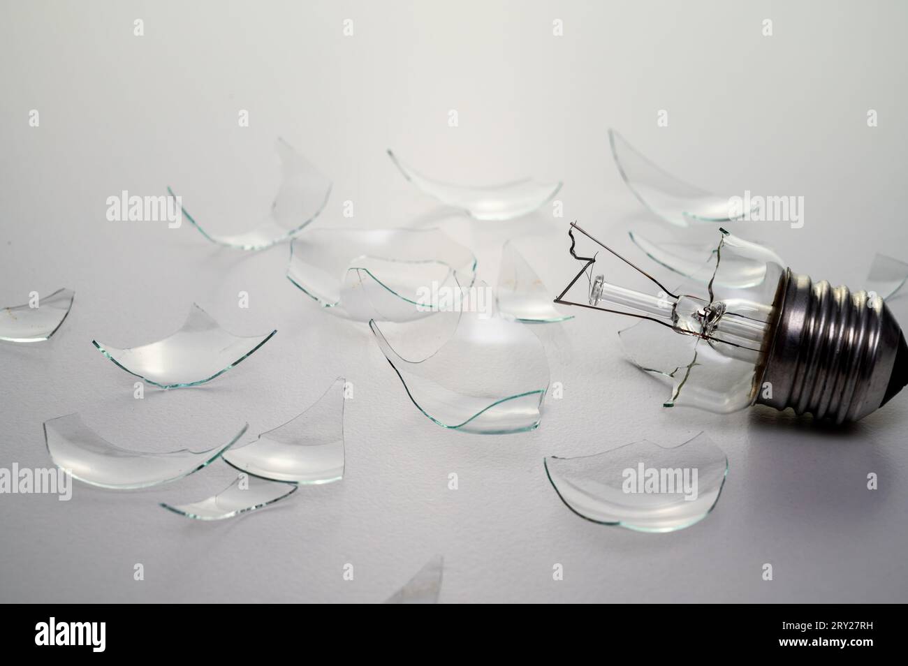 Broken light bulb, with shards of transparent glass around it, on a ...