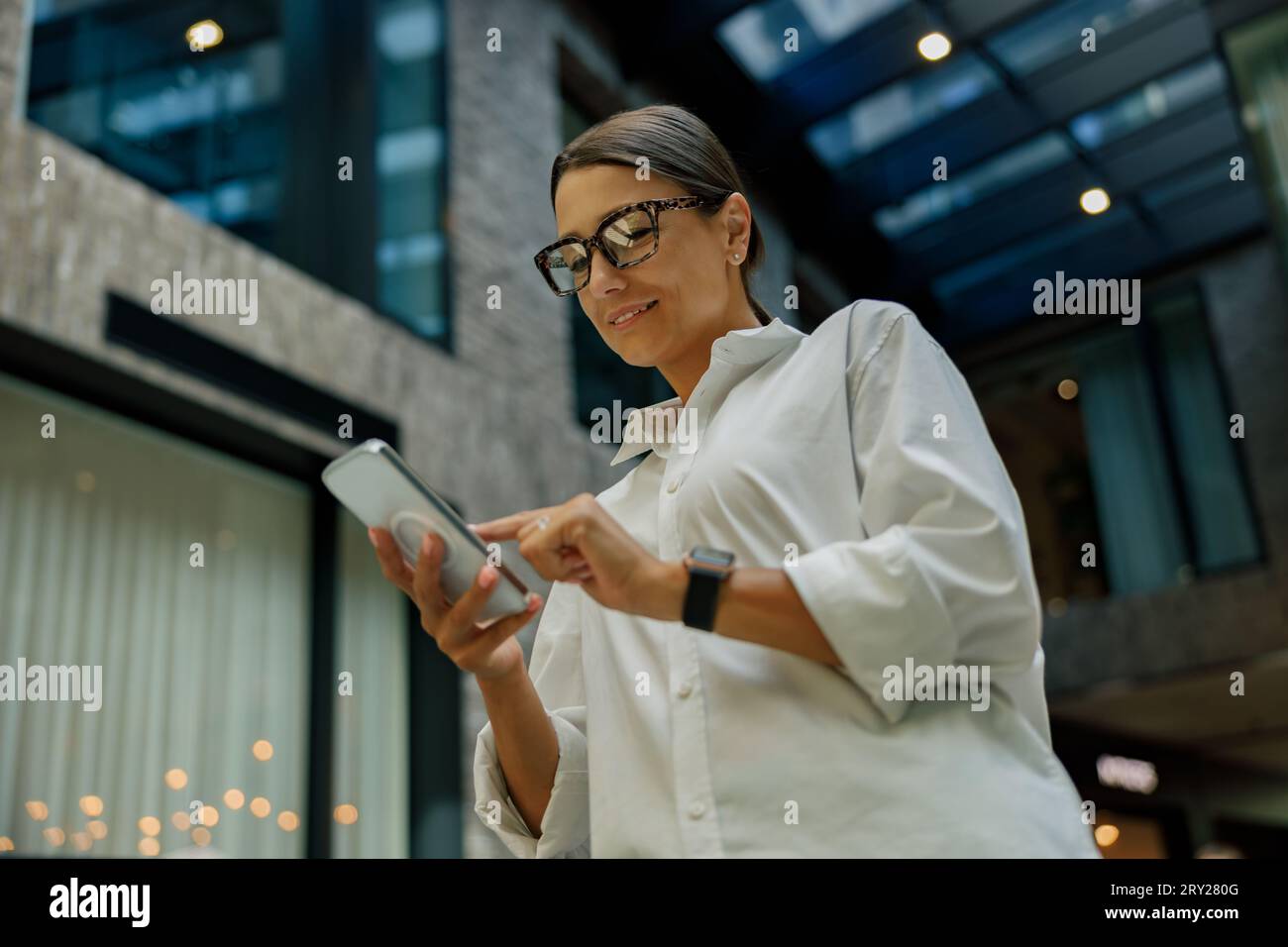 Focused woman entrepreneur use mobile phone while standing on office ...